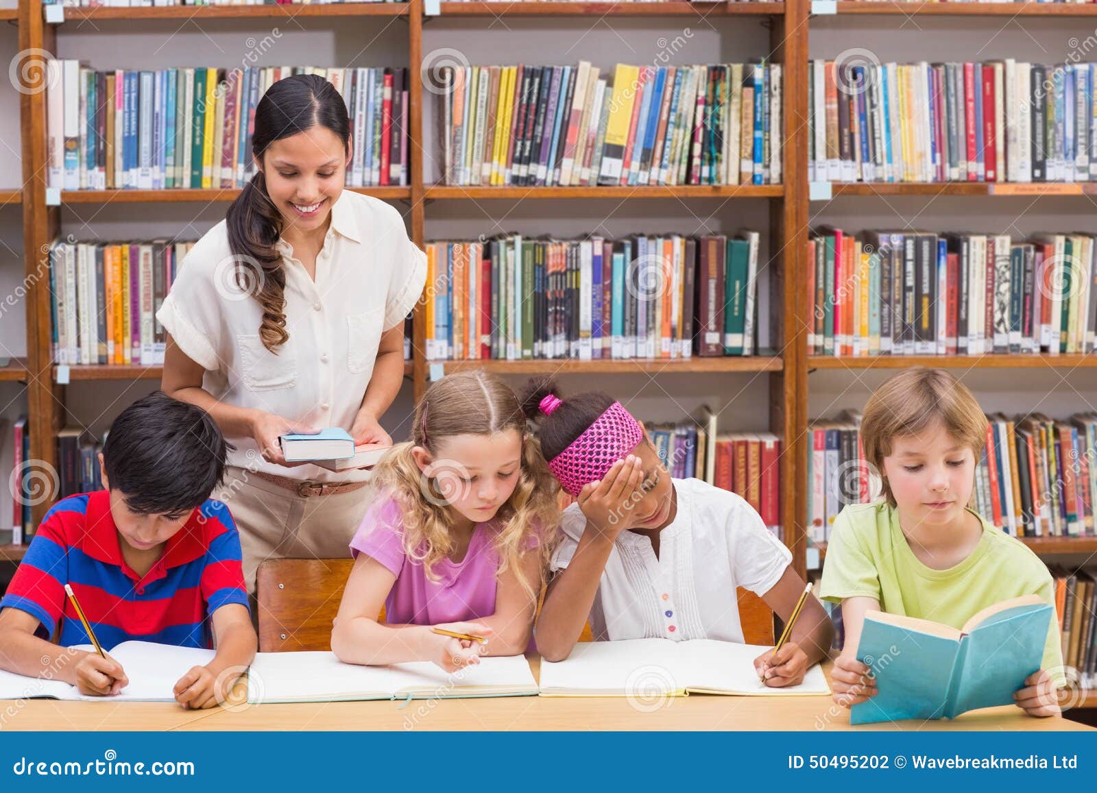Pretty Teacher Helping Pupils in Library Stock Photo - Image of ...