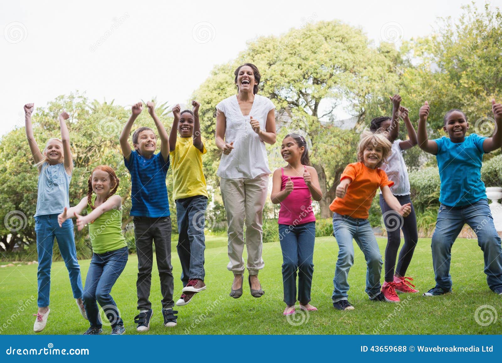 Pretty Teacher Jumping with Pupils Outside Stock Photo - Image of girl ...
