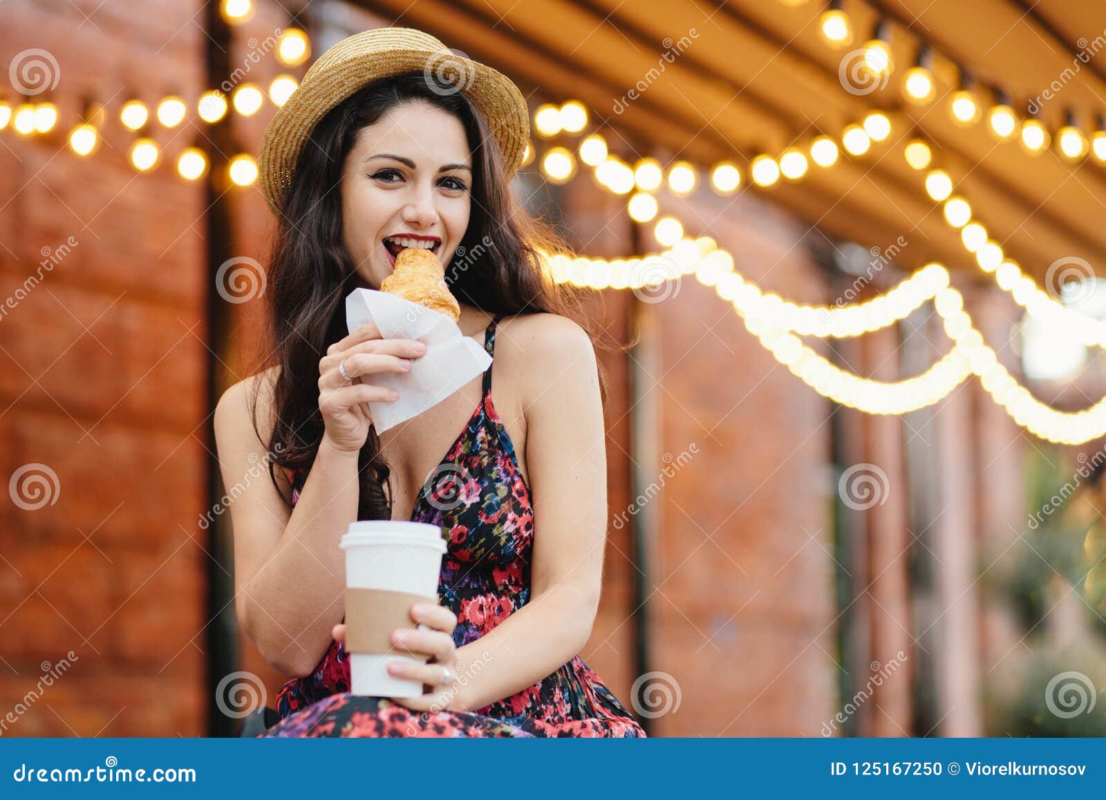 Pretty Woman With Dark Hair Shining Eyes Eatting With Pleasure Tasty Croissant And Drinking