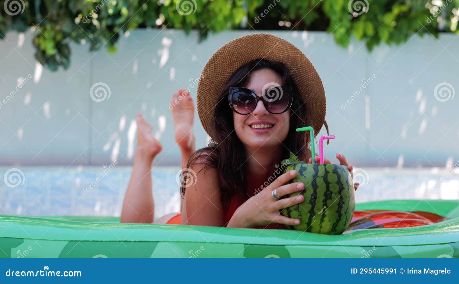 Pretty Woman In Straw Hat And Sunglasses Lying On Inflatable Watermelon