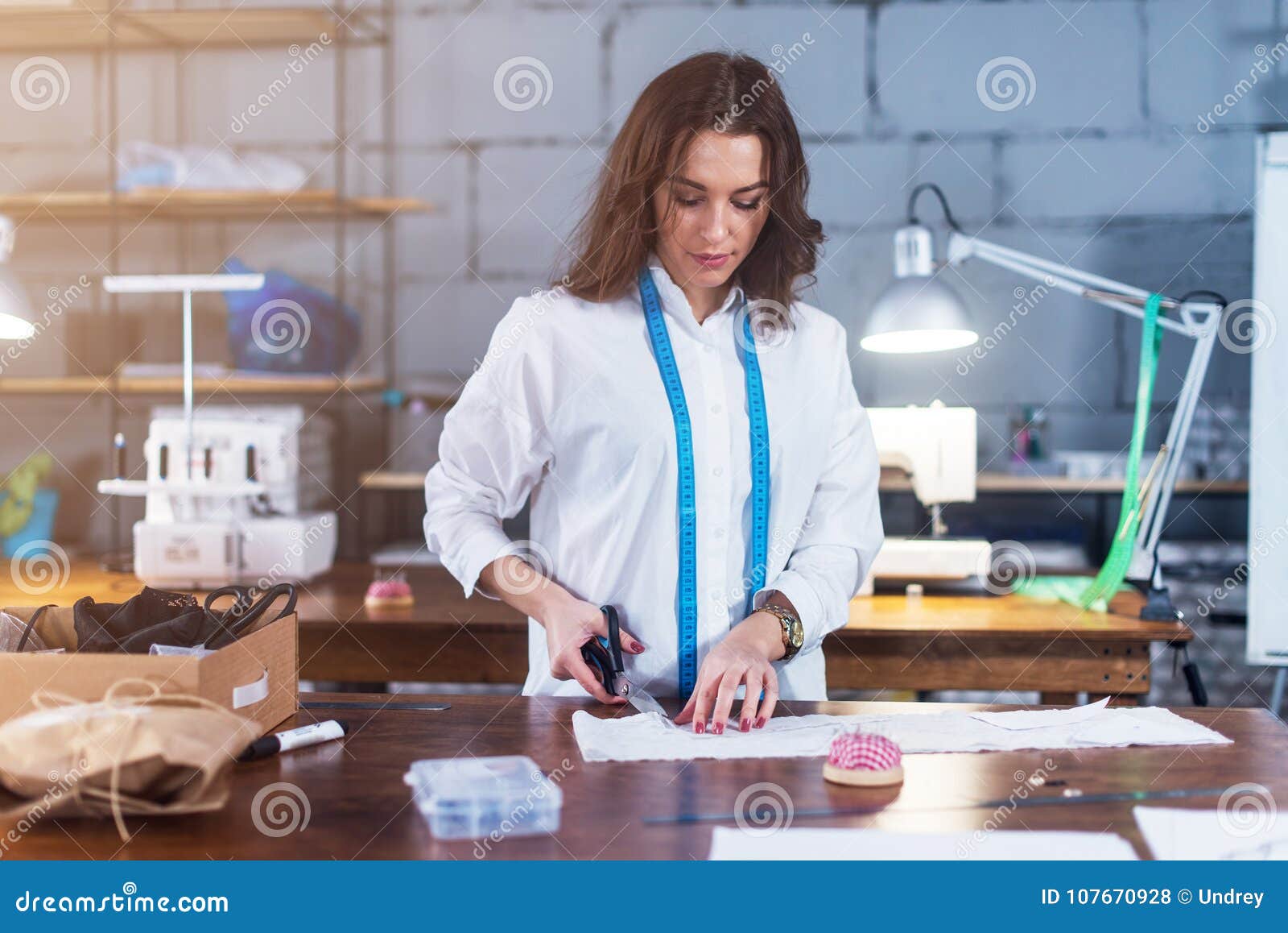 Pretty Young Fashion Designer Cutting Cloth Using Scissors while ...