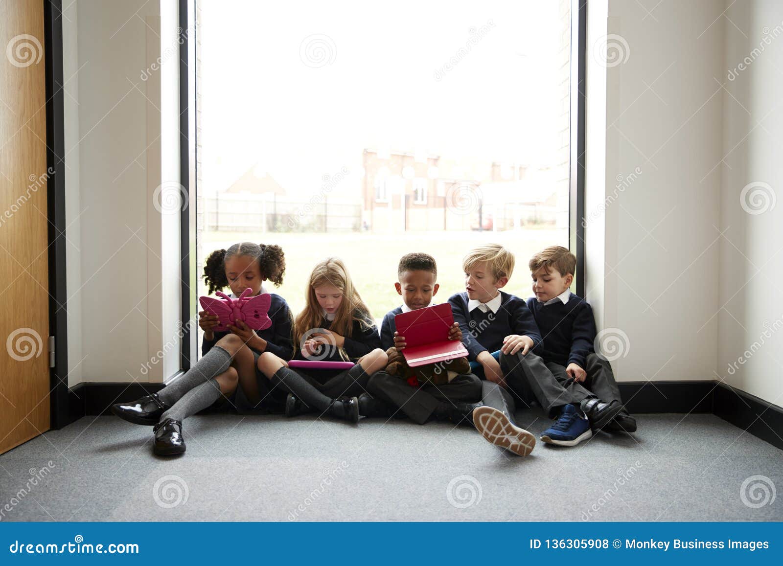 Primary School Kids Sitting in a Row on the Floor in Front of a Window ...