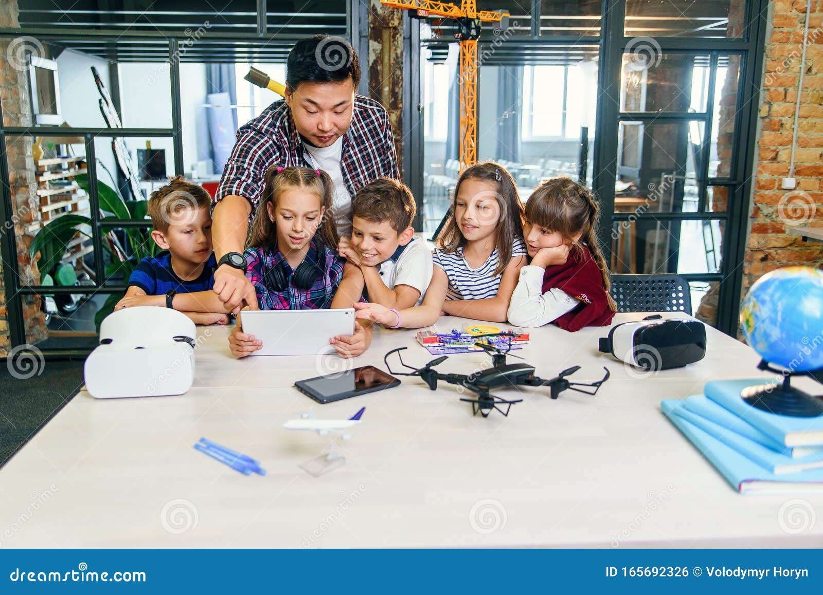 School Teacher at Desk Works with Five Young Pupils Using Digital ...