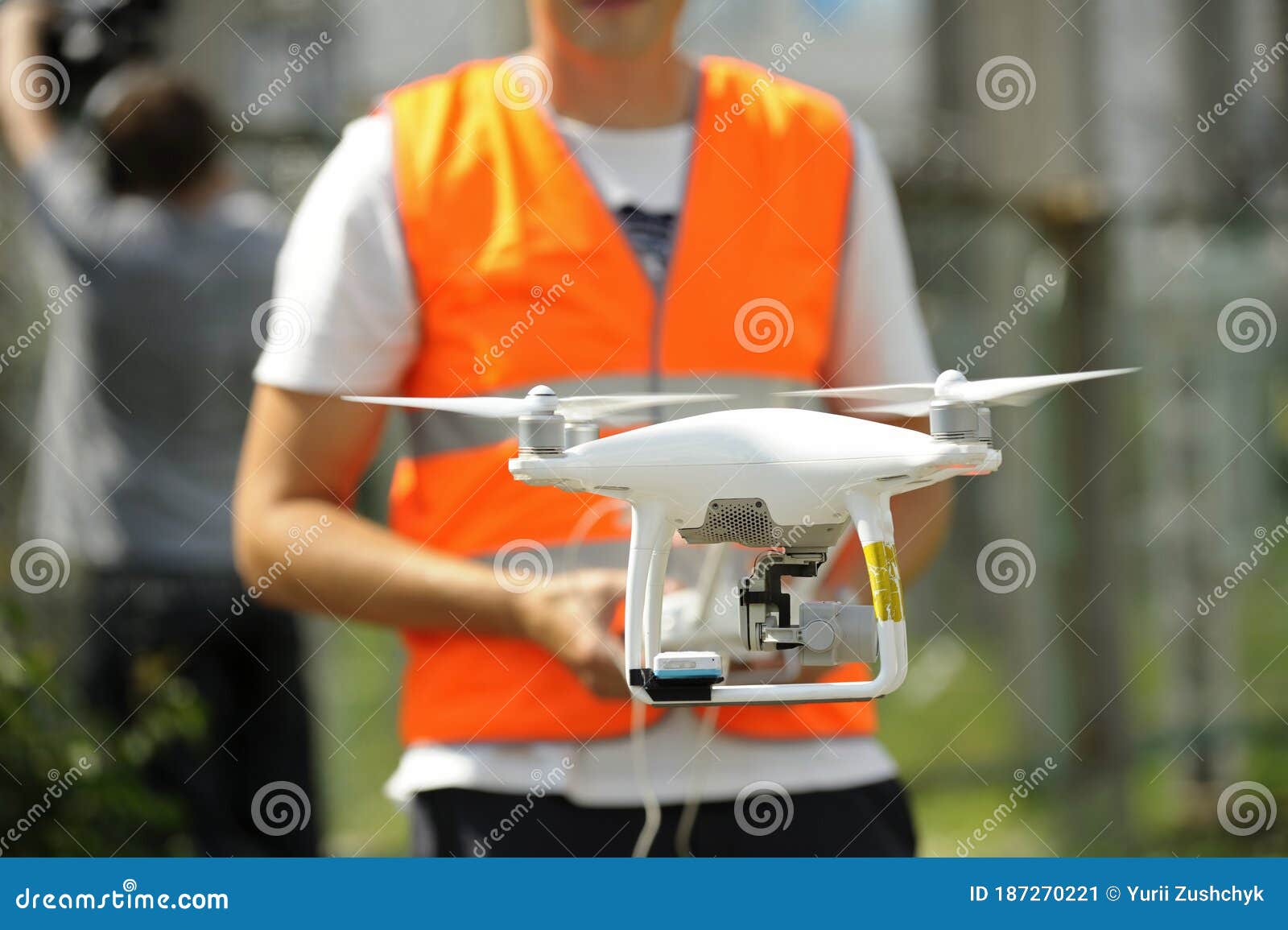 Pro Quadcopter with Camera Aboard Flying, Operator Controlling it on a ...