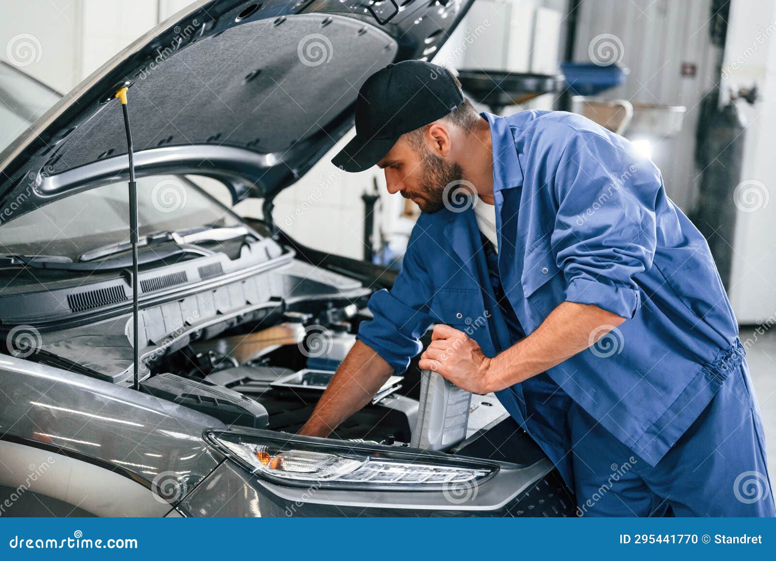 Process of Changing the Oil. Auto Mechanic Working in Garage Stock ...