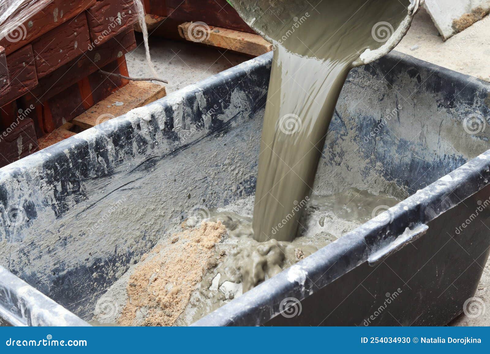 The Process of Mixing Cement at a Construction Site. Pouring Water into ...