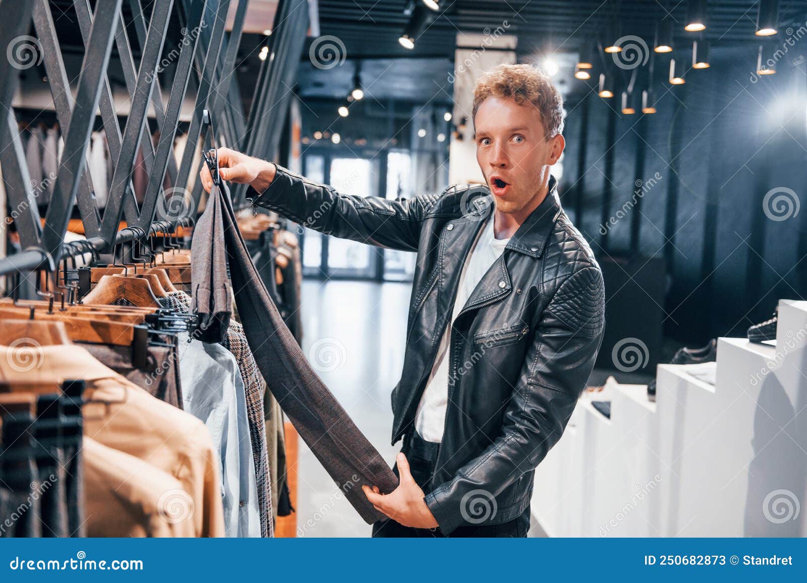 Productos De Calidad. Chico Joven De Tienda Moderna Con Ropa Nueva ... Productos De Calidad. Chico Joven De Tienda Moderna Con Ropa Nueva ...