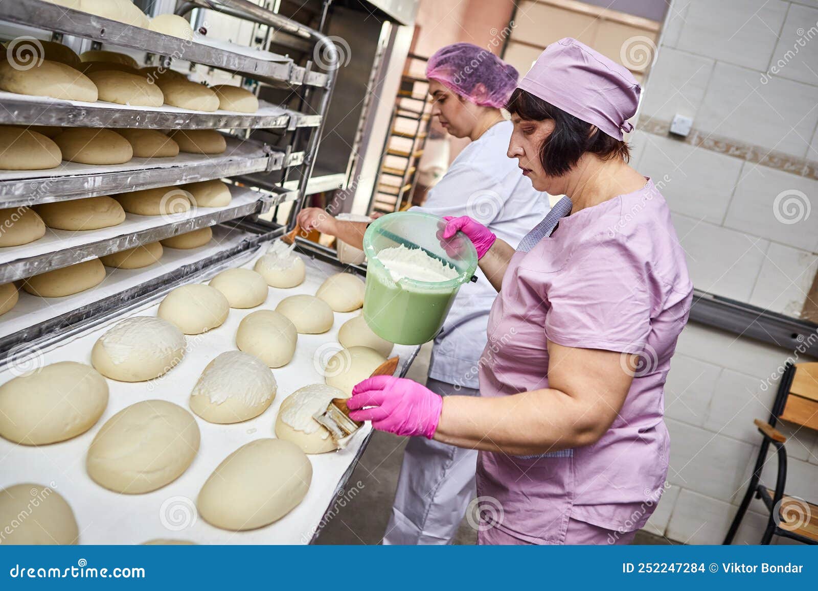 Professional Baker in Uniform Smears Butter Bread Dough for Baking at ...
