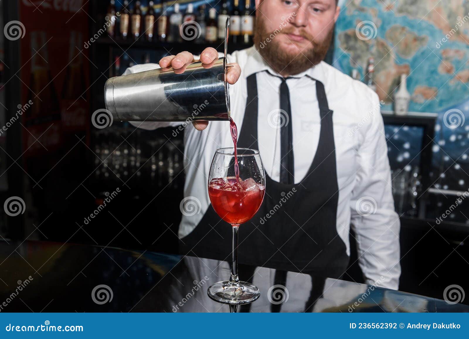 Professional Bartender with a Beard Pours Liquid into a Glass of Ice ...