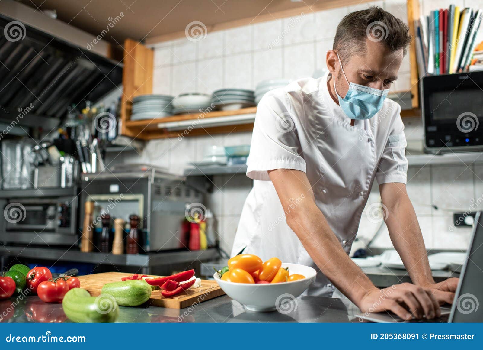 Professional Chef in Uniform and Protective Mask Looking through Online ...