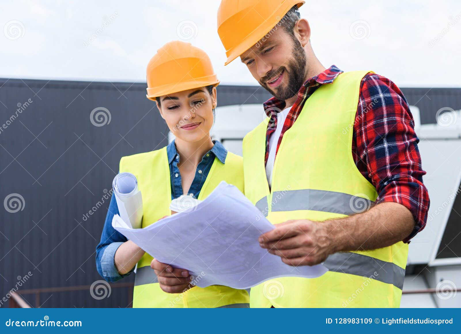 Professional Constructors in Hardhats Working with Blueprints Stock ...