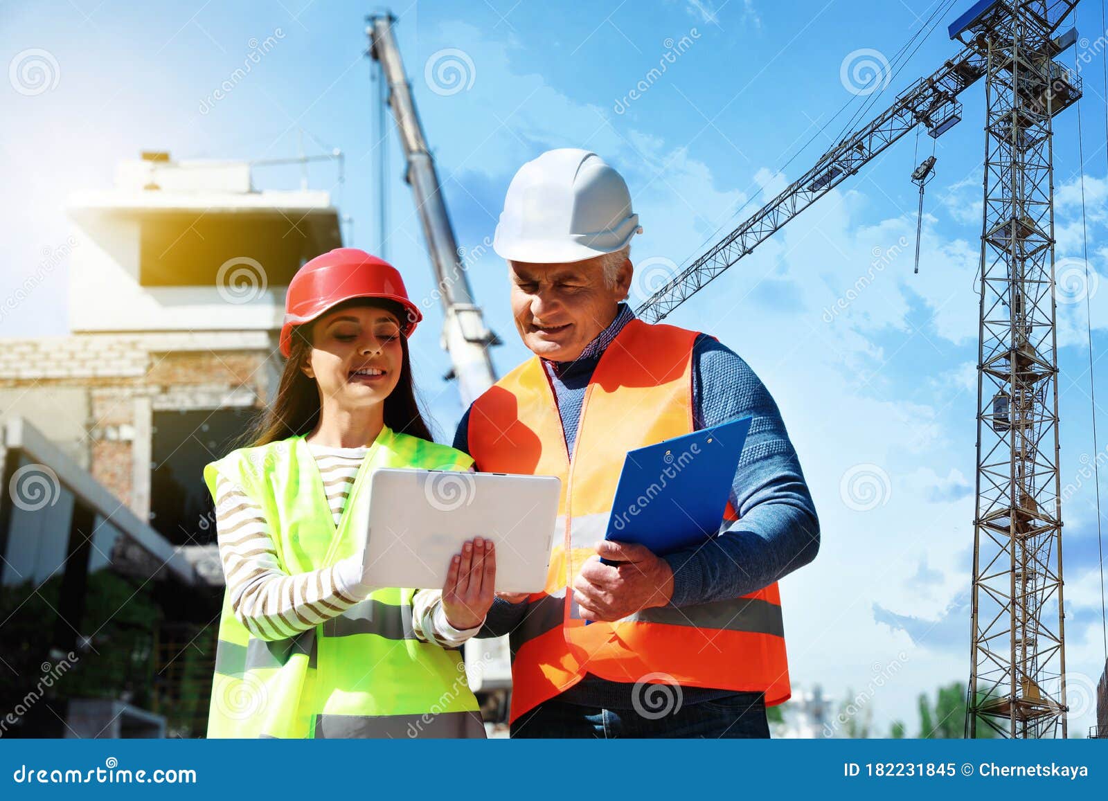 Engineer and Foreman in Safety Equipment with Tablet at Construction ...