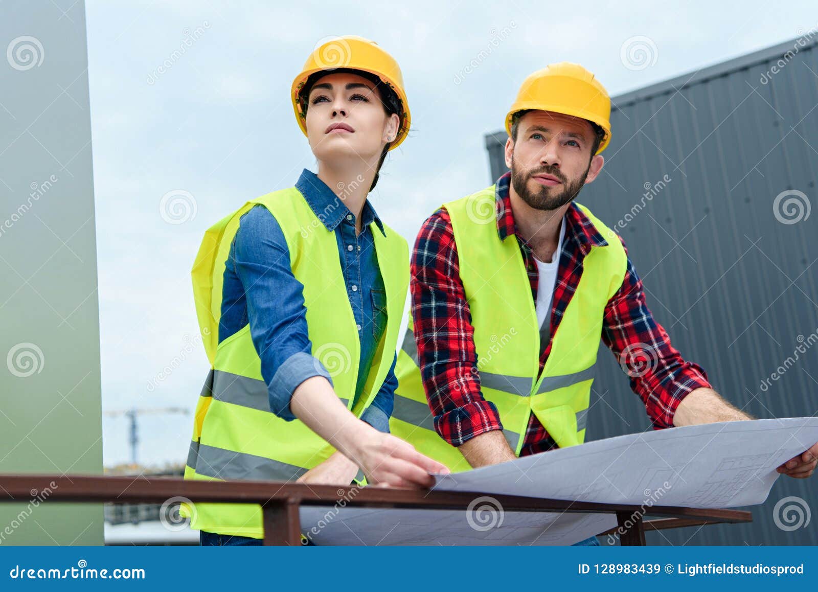 Professional Engineers in Helmets Working with Blueprints and Looking ...