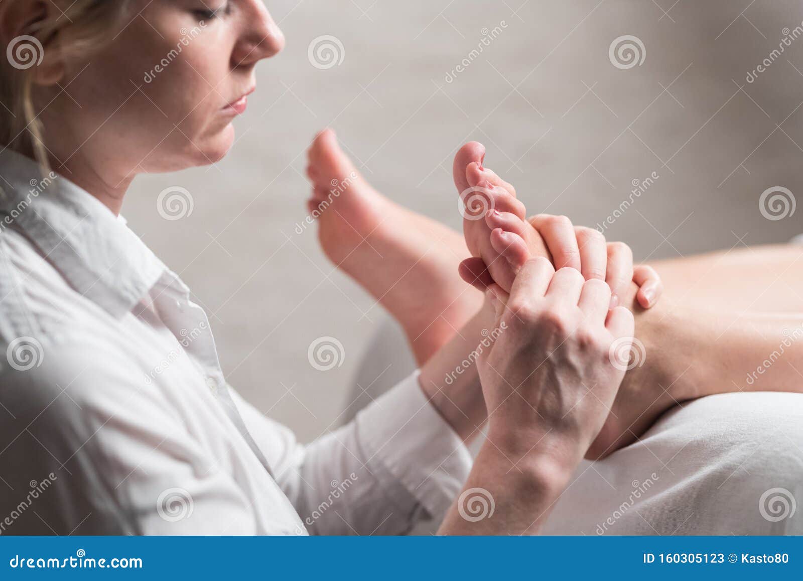 Professional Female Masseur Giving Reflexology Massage To Woman Foot