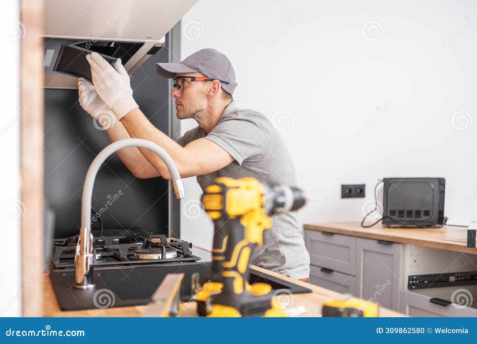 A Kitchen Installer Attaches The Hanging Mechanism To The Wall Stock ...
