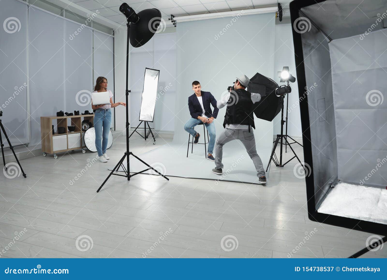 Professional Photographer with Assistant Taking Picture of Young Man in ...