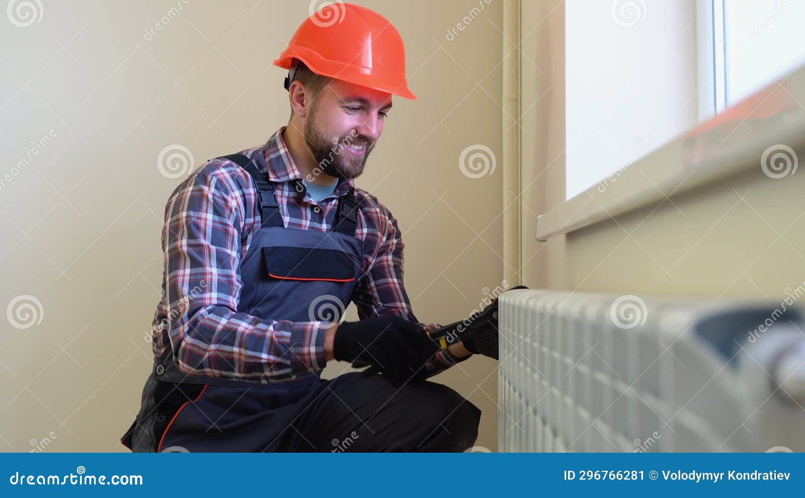 Professional Plumber in a Hard Hat and Gloves Installing Radiator in a ...