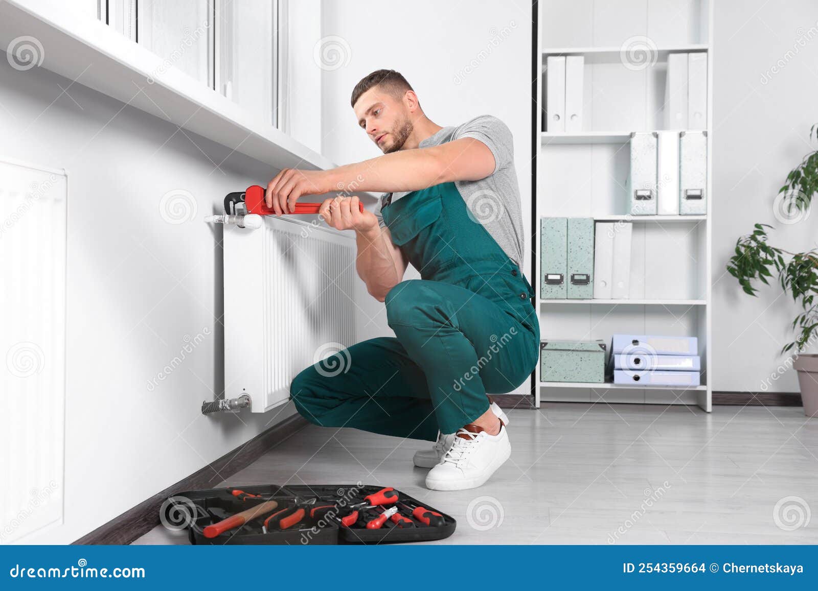 Professional Plumber Using Adjustable Wrench for Installing Heating ...