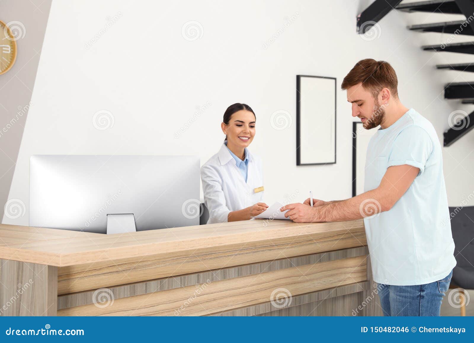 Professional Receptionist Working with Patient at Desk Stock Photo ...