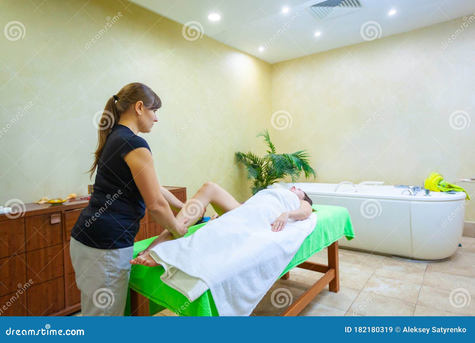 Professional Therapist Giving Relaxing Reflexology Thai Oil Leg Massage Treatment To A Woman In