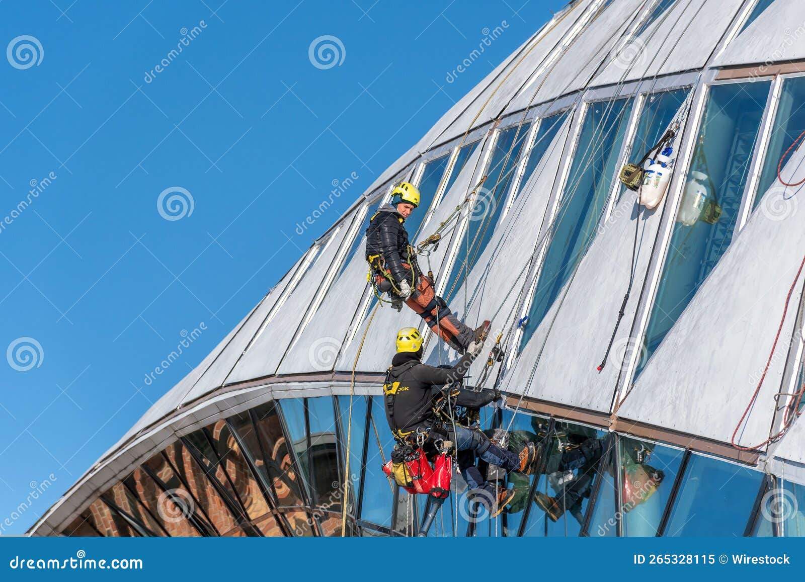 Professional Window Cleaners Hanging on Side of Modern Building Against ...