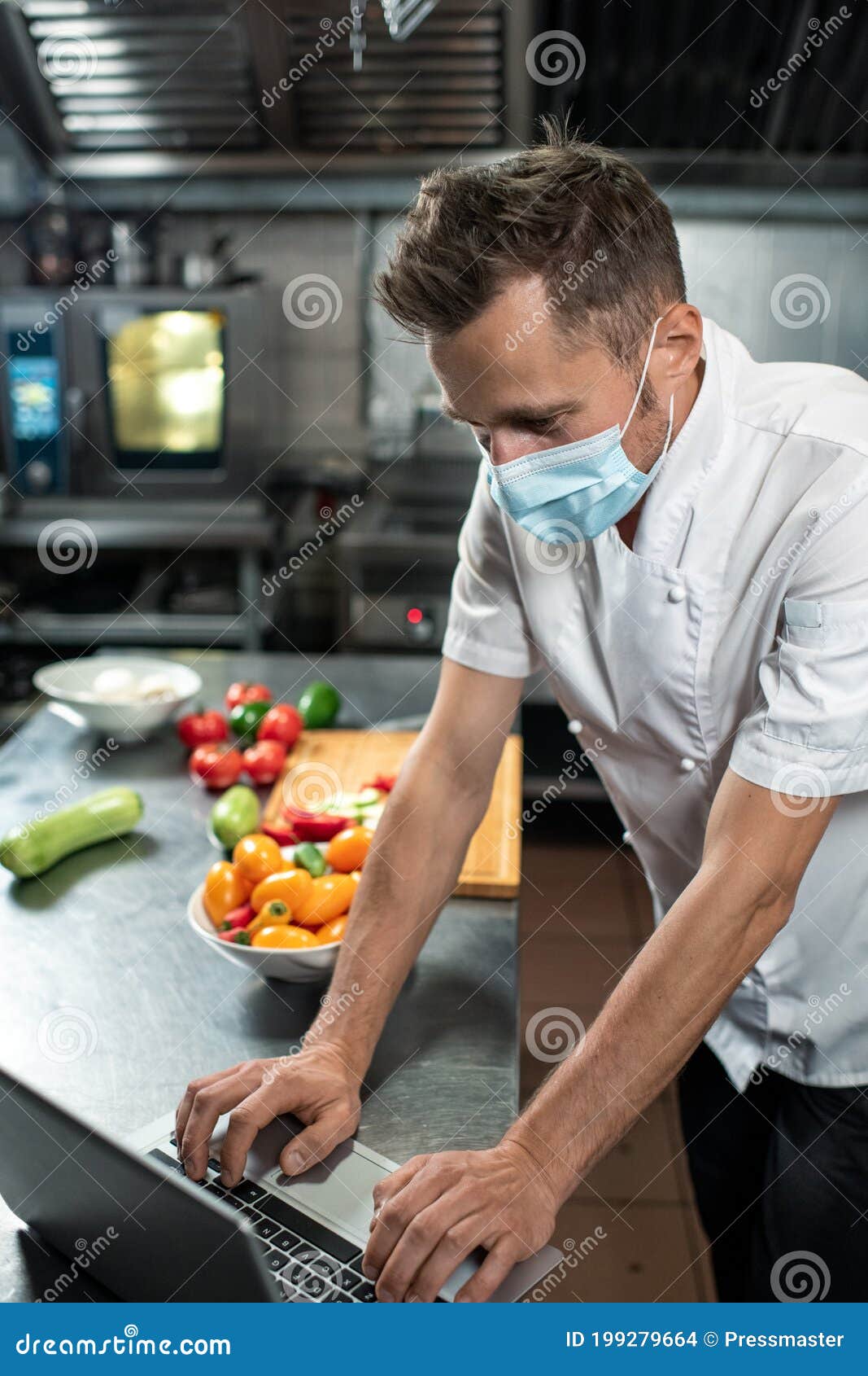 Professional Young Chef in Uniform and Protective Mask Using Laptop at ...