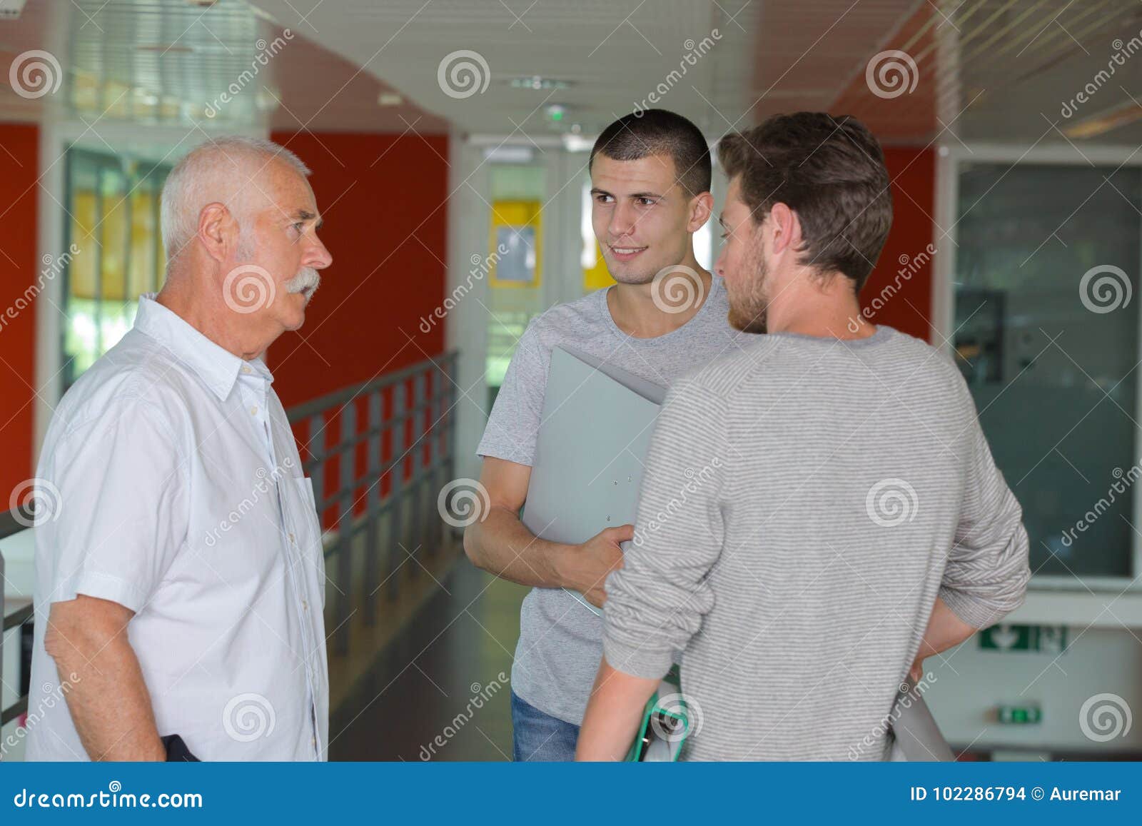 Professor with Notebook Talking To Student in Corridor Stock Photo ...