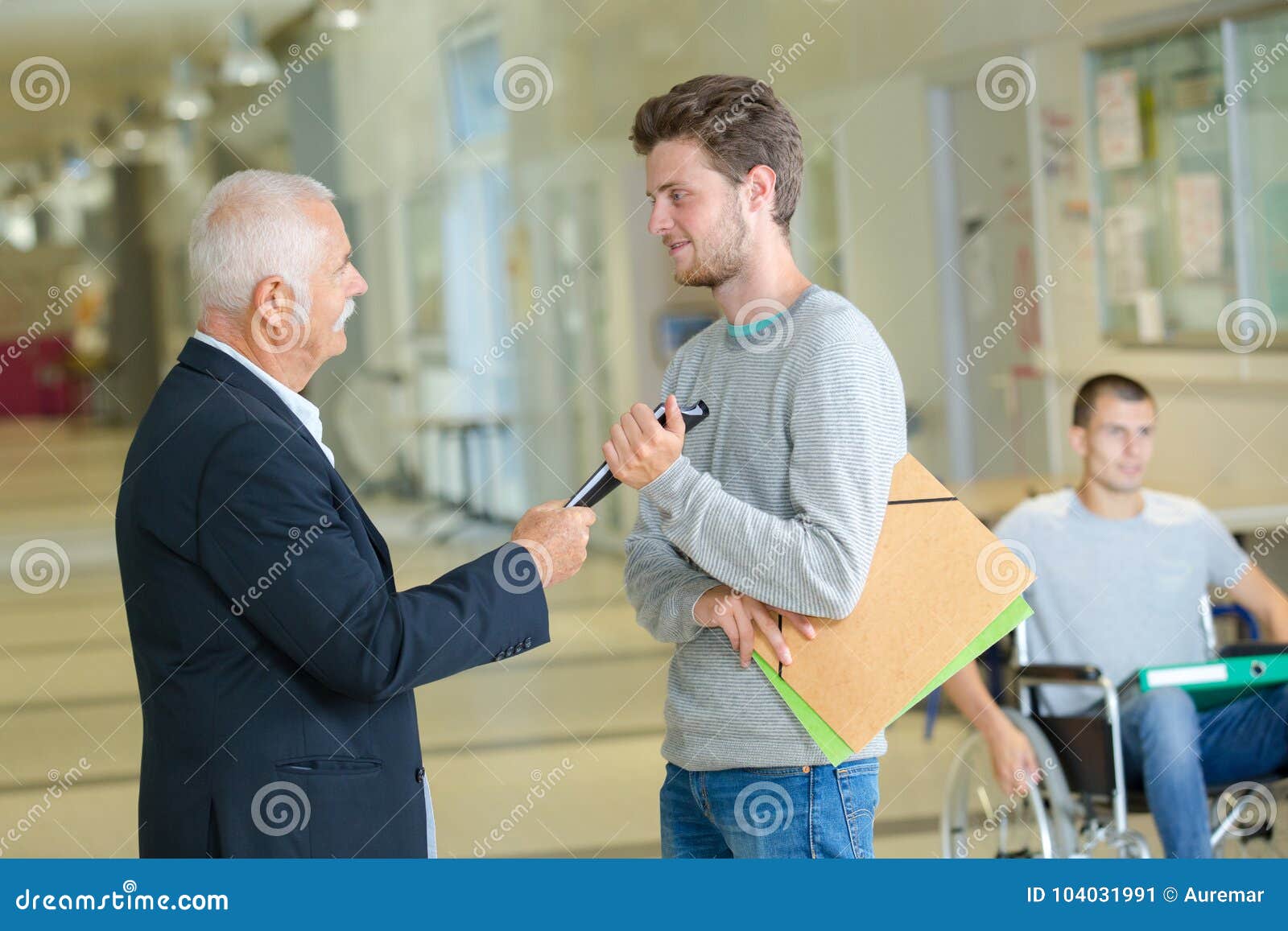 Professor with Notebook Talking To Student in Corridor Stock Image ...