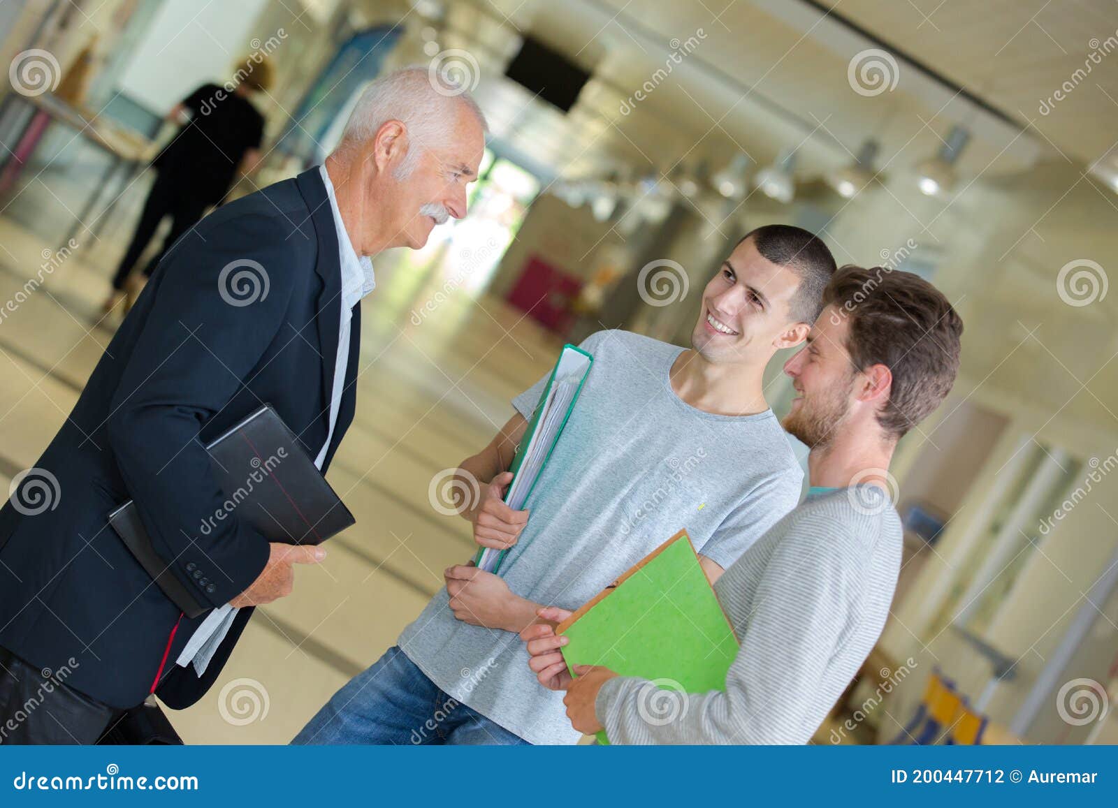 Professor with Notebook Talking To 2 Students in Corridor Stock Photo ...