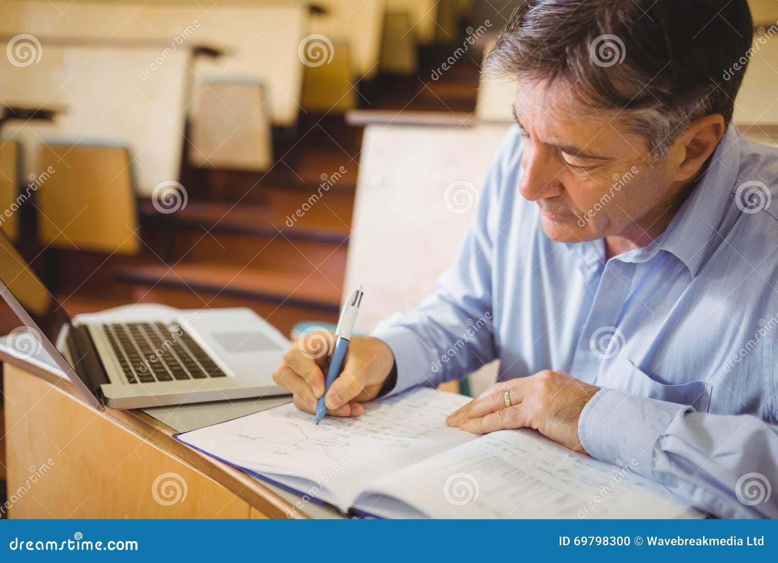 Professor Writing in Book at Desk Stock Photo - Image of laptop ...