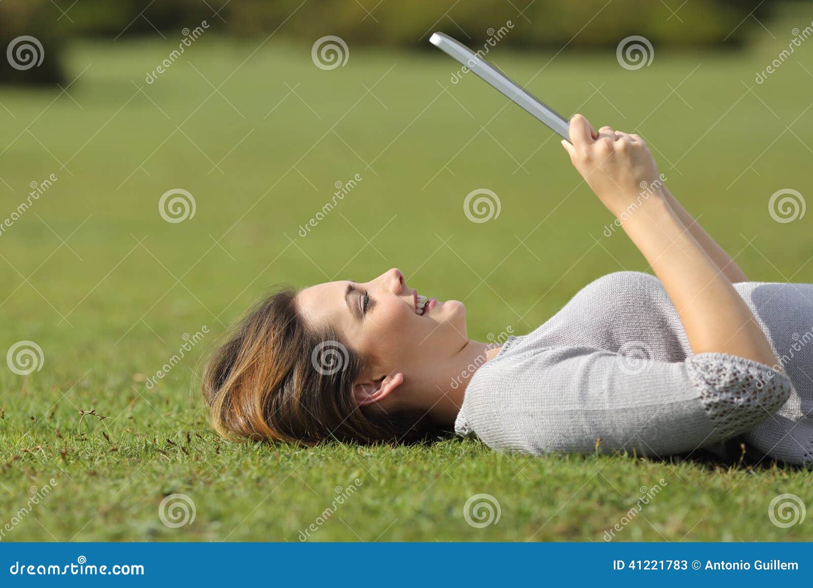 Profile of a Happy Woman Reading a Tablet Reader on the Grass Stock ...