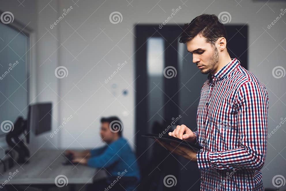Side View of Young Programmer Standing in the Office Looking Down at ...