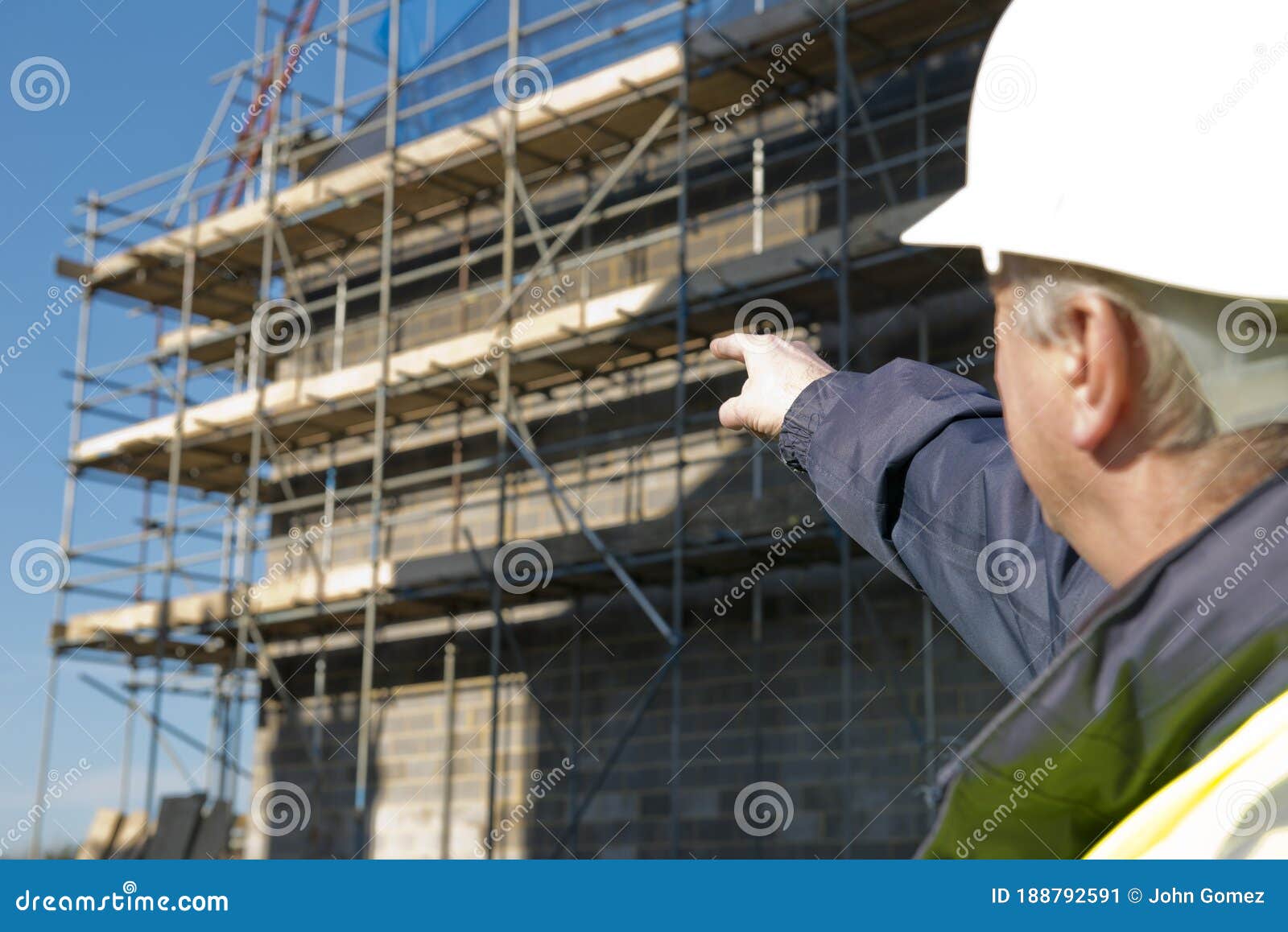 Property Developer / Builder Pointing at Building with Scaffolding ...