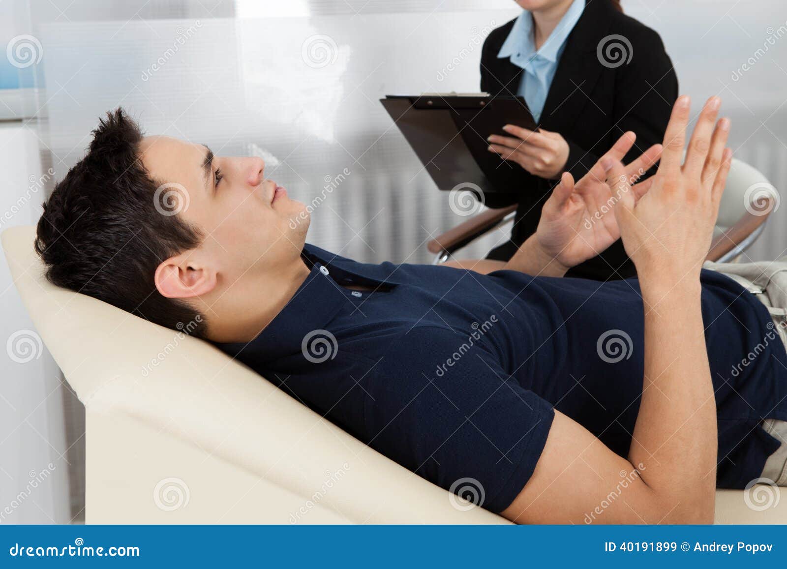Psychologist Writing Notes While Patient Lying On Bed Stock Image