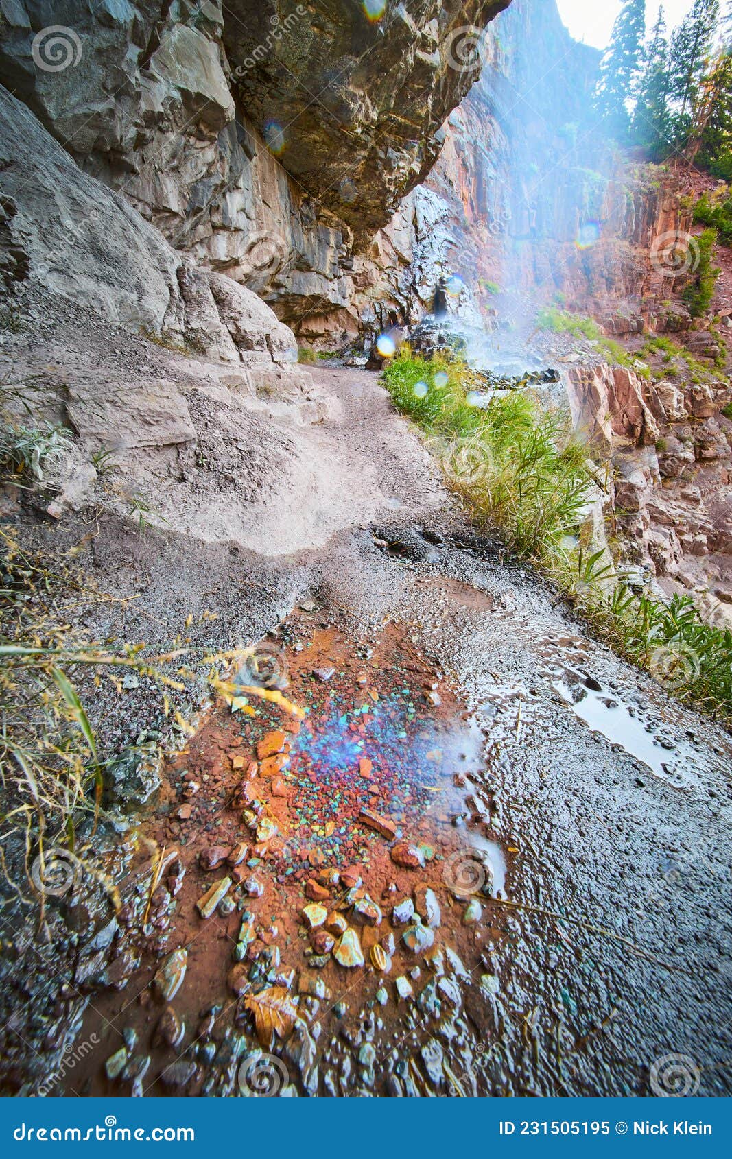 Puddle with Colorful Rocks Next To Waterfall Over Large Cliffs Stock ...