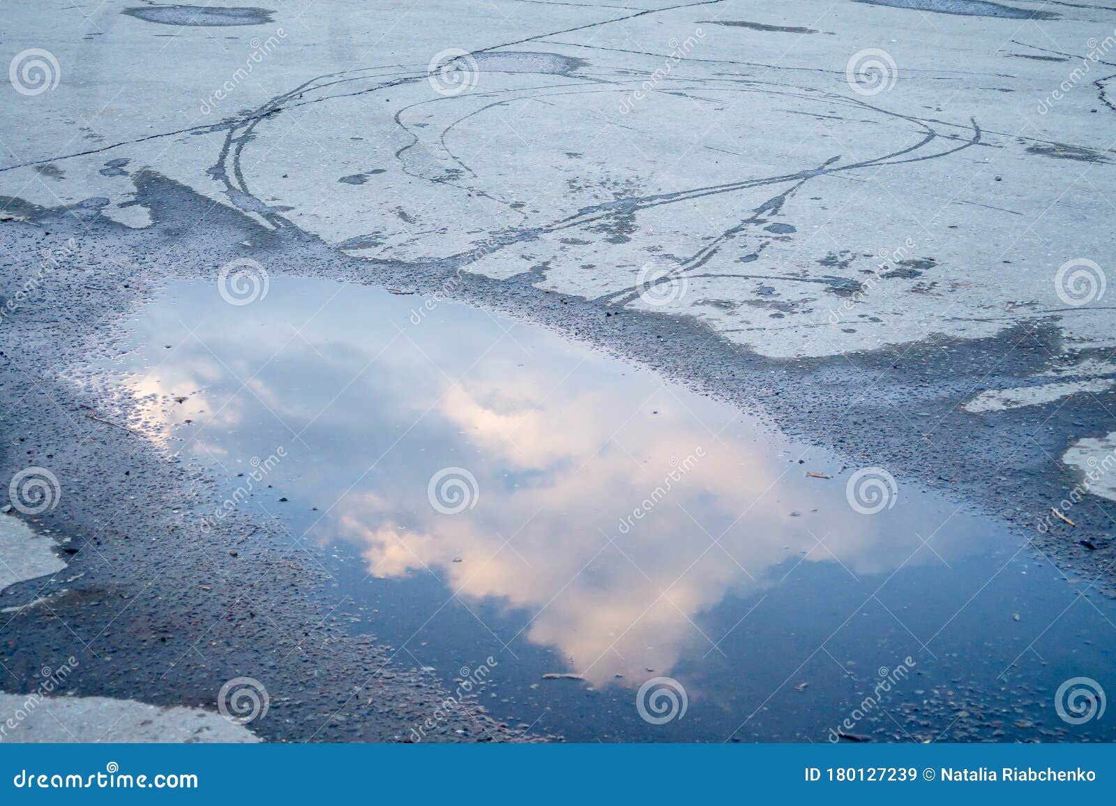 A Puddle on the Paved Road. Reflection of the Blue Sky and White Clouds ...