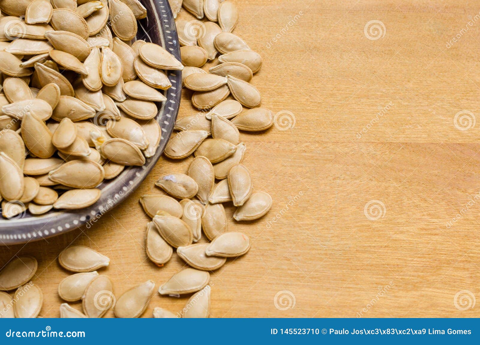 Pumpkin Seeds Inside a Small Bowl, with Some Seeds Below, on a Light ...