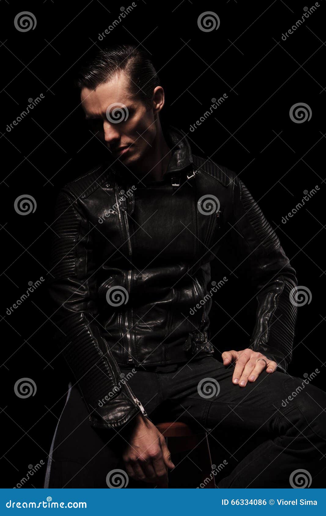 Punk Model in Leather Jacket Posing Seated in Dark Studio Stock Photo ...