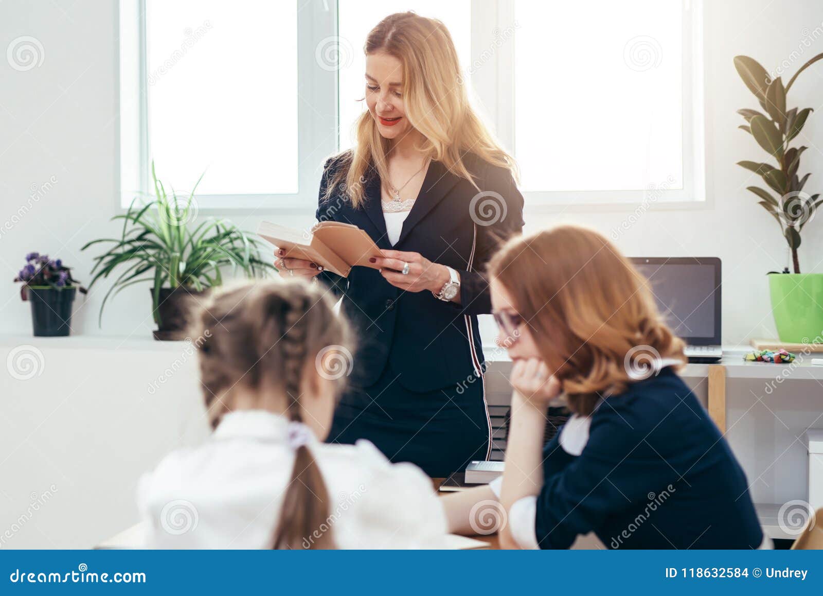 Pupils and Teacher Reading Book in Classroom Stock Photo - Image of ...