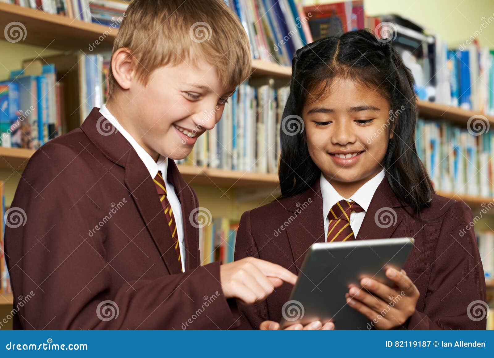 Pupils Wearing School Uniform Using Digital Tablet in Library Stock ...