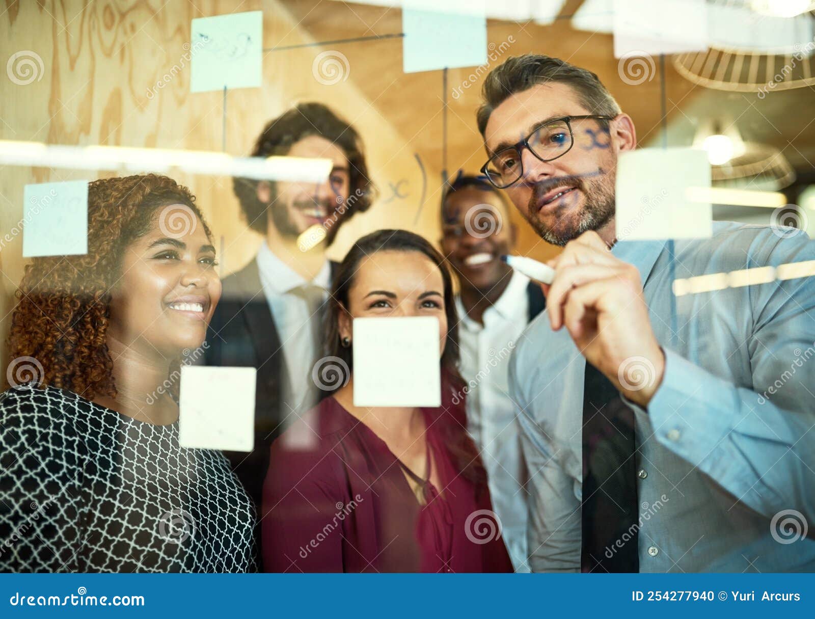 Putting the Ideas into Focus. Coworkers Using Sticky Notes on a Glass ...
