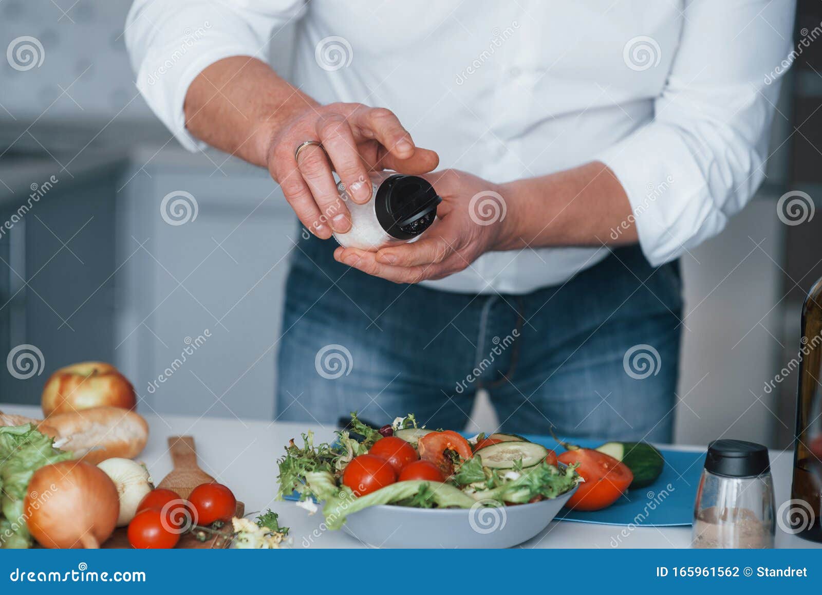 Putting Some Salt. Man in White Shirt Preparing Food on the Kitchen ...