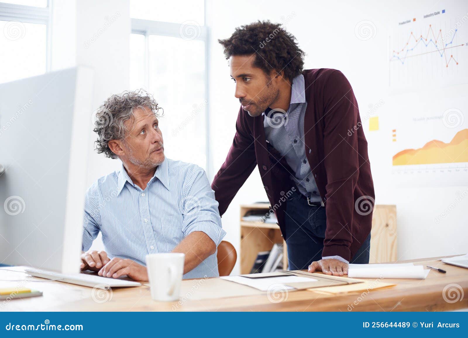 Putting Their Heads Together. Two Coworkers in an Office Discussing ...