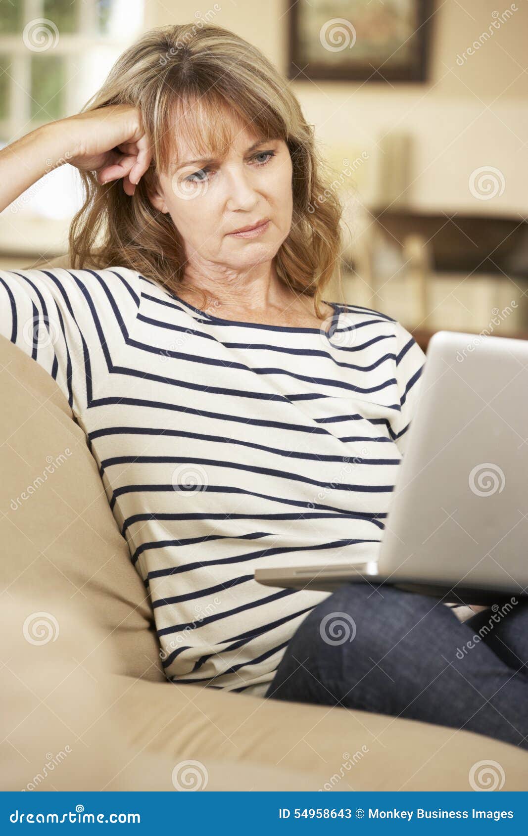 Puzzled Mature Woman Sitting on Sofa at Home Using Laptop Stock Image ...