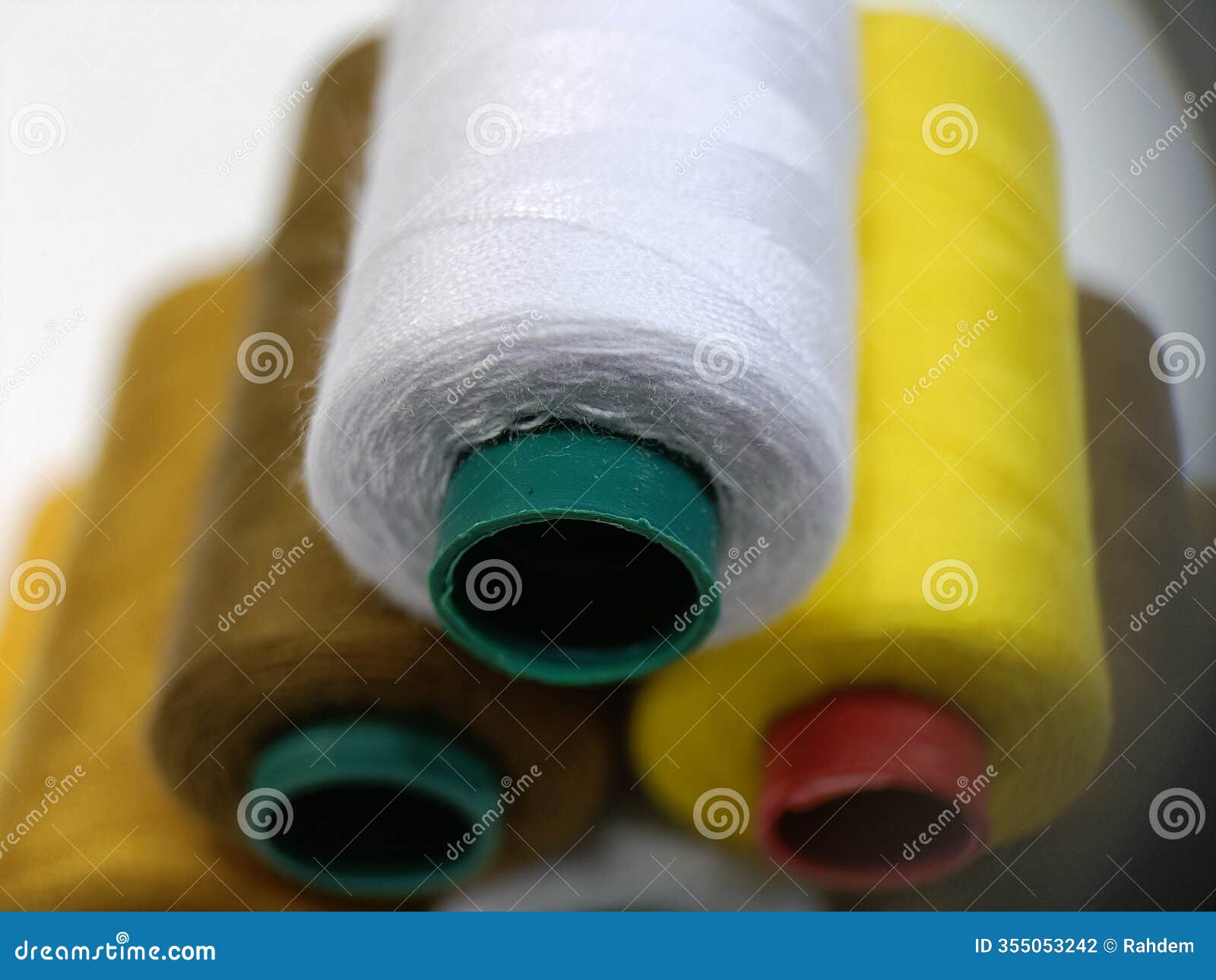 Pyramid Stack of Yellow, White, and Brown Sewing Thread Spools on White ...
