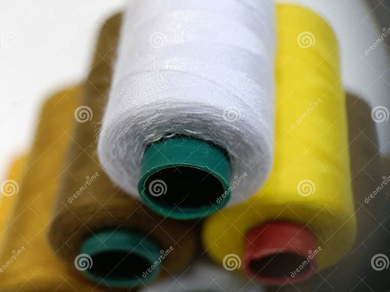 Pyramid Stack of Yellow, White, and Brown Sewing Thread Spools on White ...