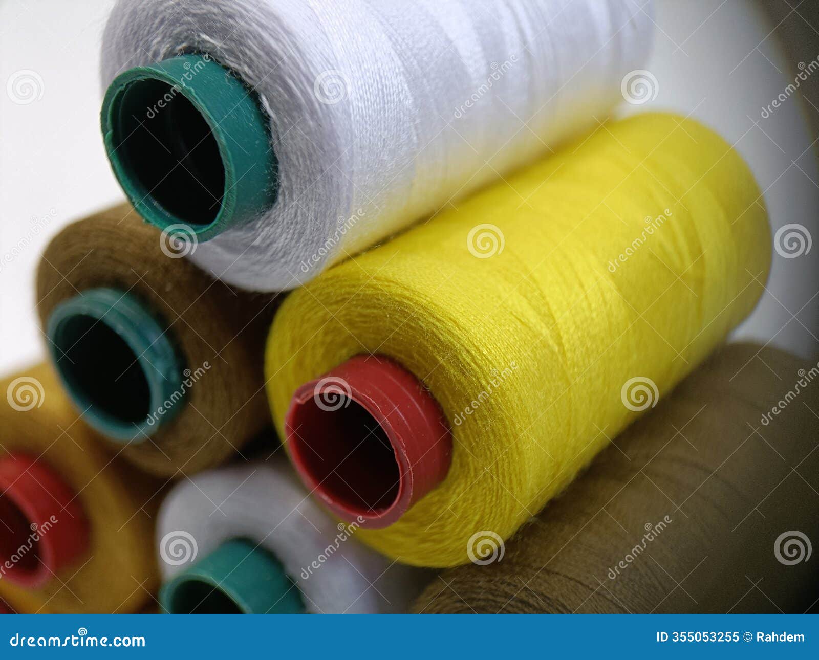 Pyramid Stack of Yellow, White, and Brown Sewing Thread Spools on White ...