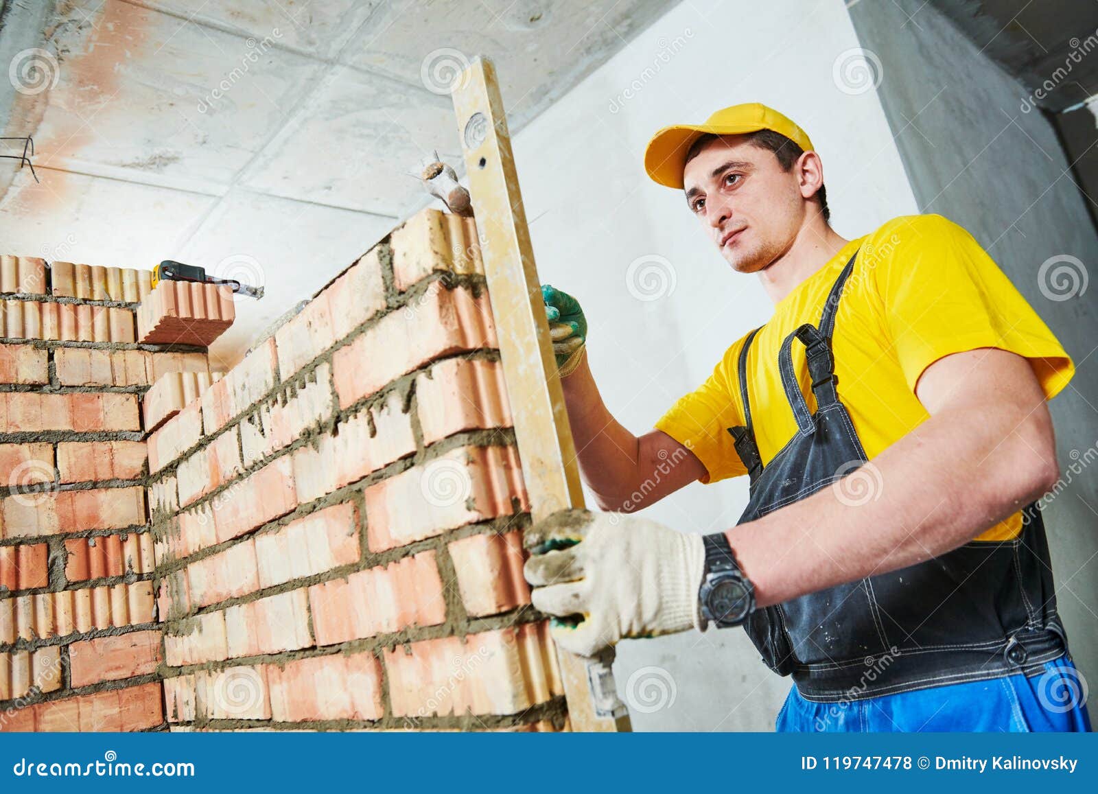 Bricklaying. Worker Checks Erected Brick Wall with Level Stock Photo ...