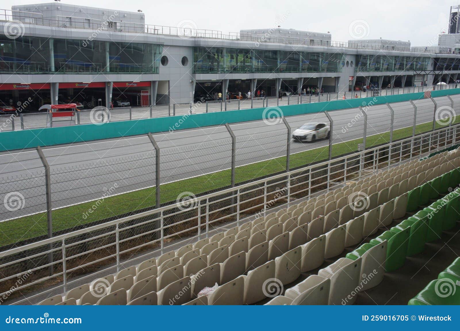 Racing Car Passes in Front of the Grandstand with the Paddock Building ...