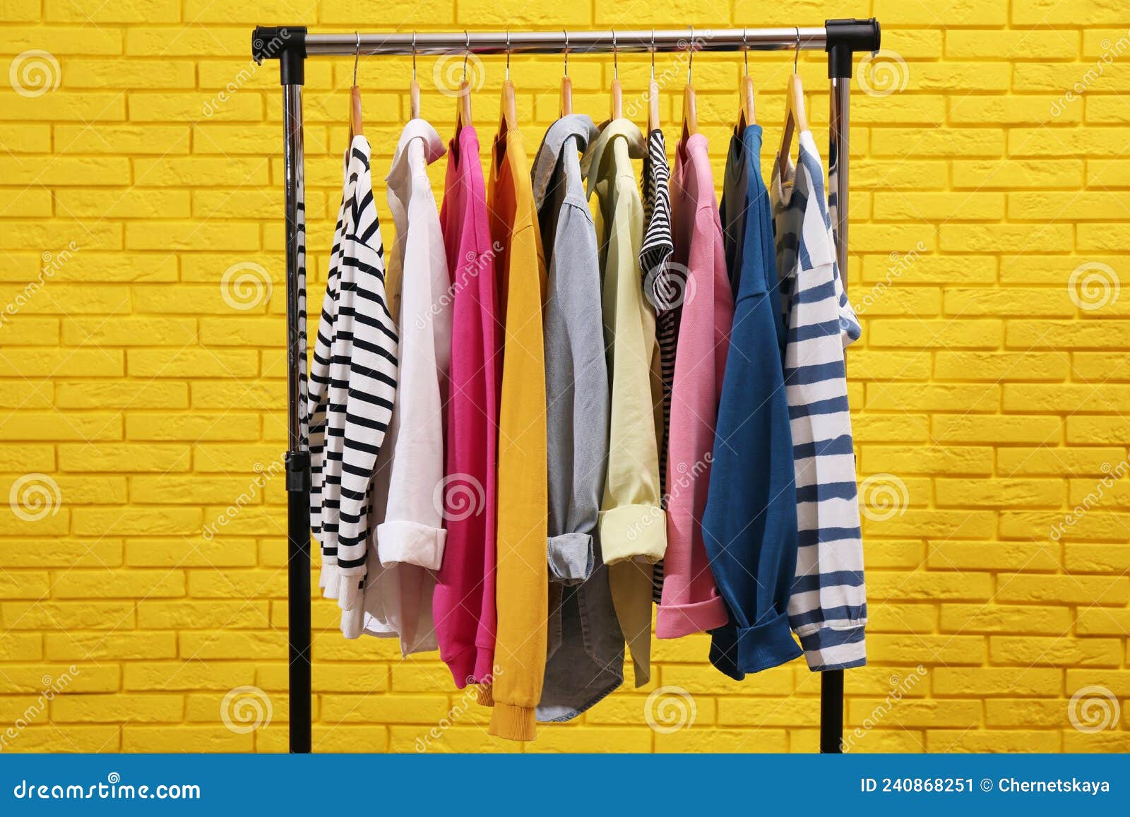 Rack with Different Stylish Clothes Near Yellow Brick Wall Stock Image ...